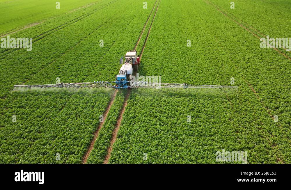 Farming tractor spraying on field with sprayer, herbicides and ...