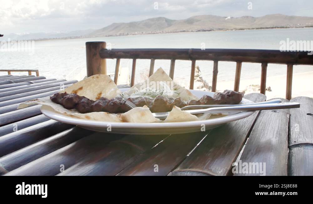 A woman's hands put a juicy meat keyua in a plate with pita bread on ...