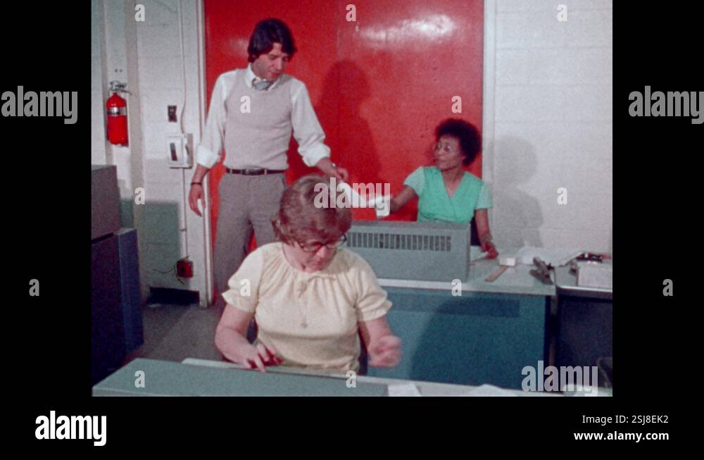 1970s: Women working at desks, man enters, takes papers from woman ...