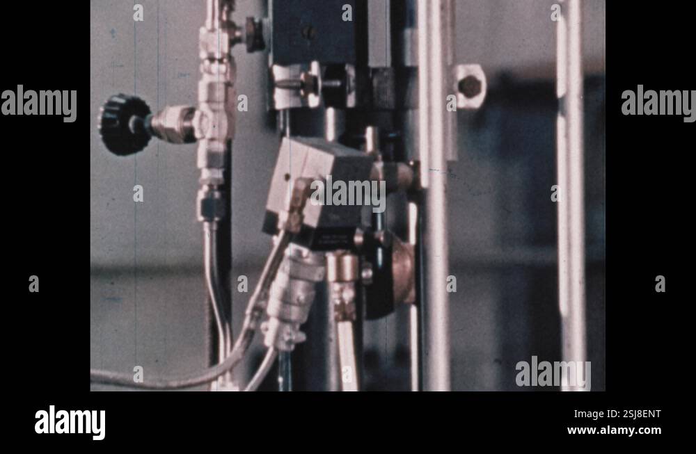 1970s: Sign reads "DANGER HIGH TEMPERATURE." Men work on hanging engine ...