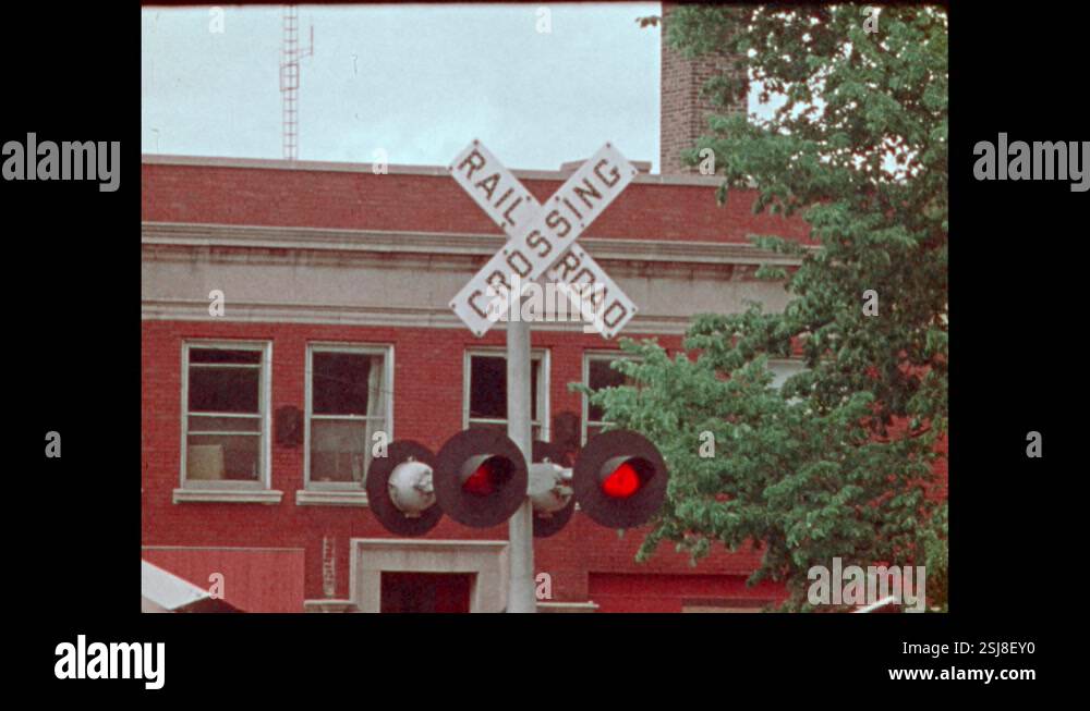 1970s: Railroad crossing, lights flashing. Train moving on tracks. Kids ...