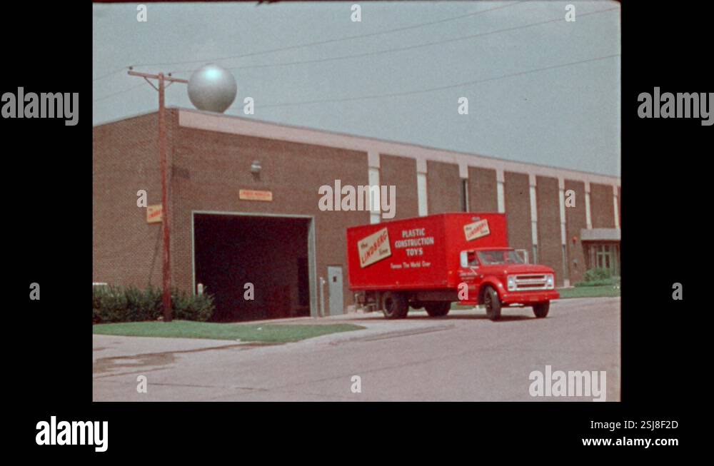 1970s: Truck driving from factory. Exterior of building, parking lot ...