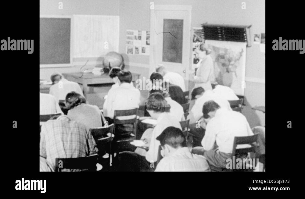 1950s: Students work quietly at their desks in classroom. Teen boy ...