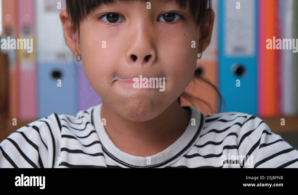 Cute Asian girl drinking a glass of milk at home. Healthy food in child ...