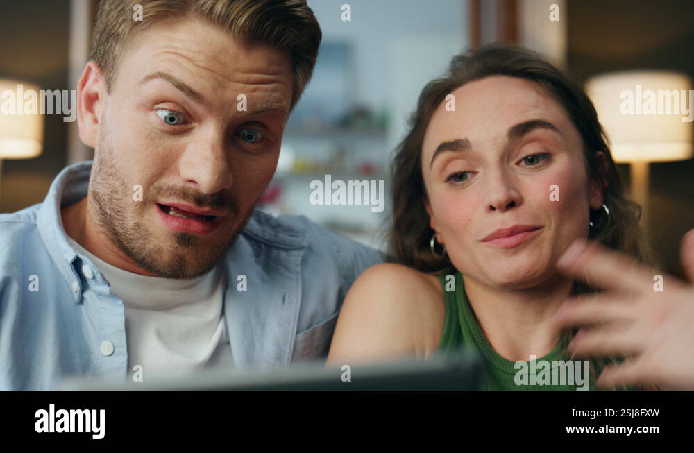 Closeup wondering pair discussing pad at home. Shocked man face opening ...