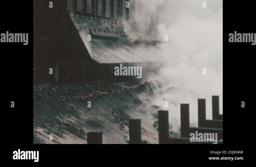 1980s: Coal pouring from oven. Shots of coal stockpile. Man in control ...