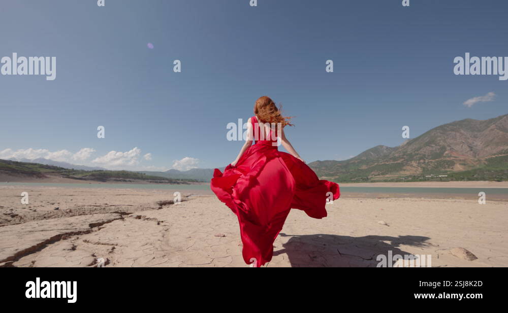 Back view of redhead woman run in red blowing dress, fashion show ...