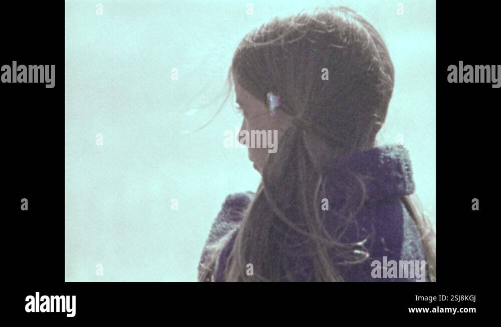 1970s: girl with long hair blowing in wind looks at water, girl looks ...