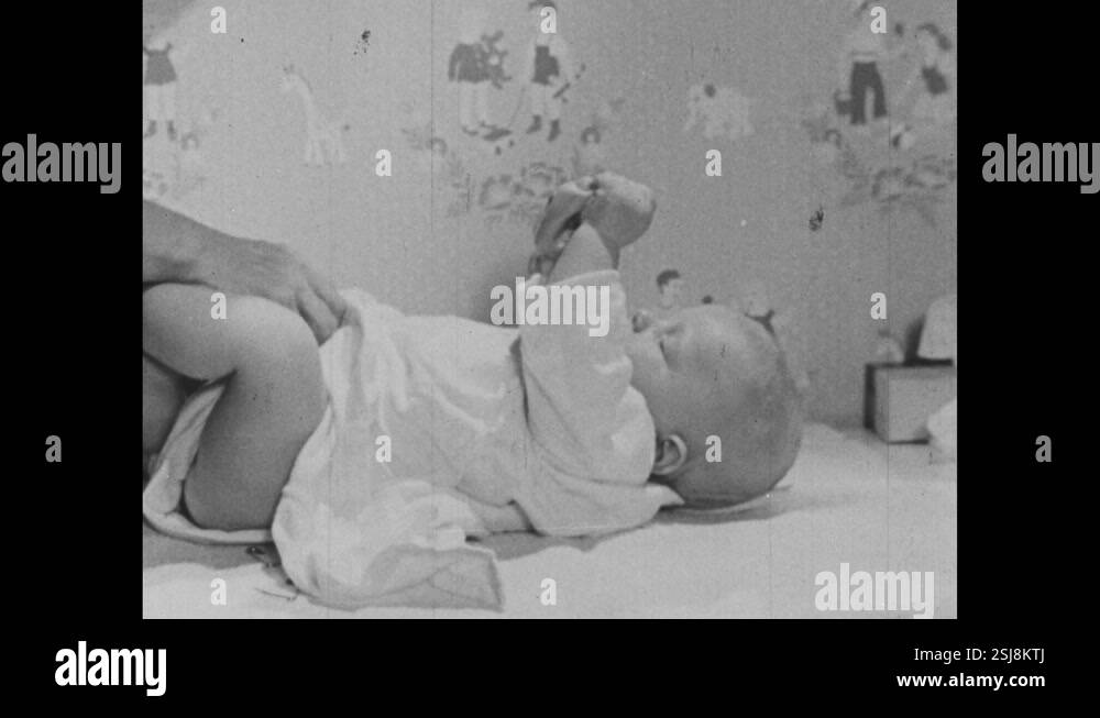 1950s: Tilt down, hands giving toy to baby. Woman tucking in baby in ...