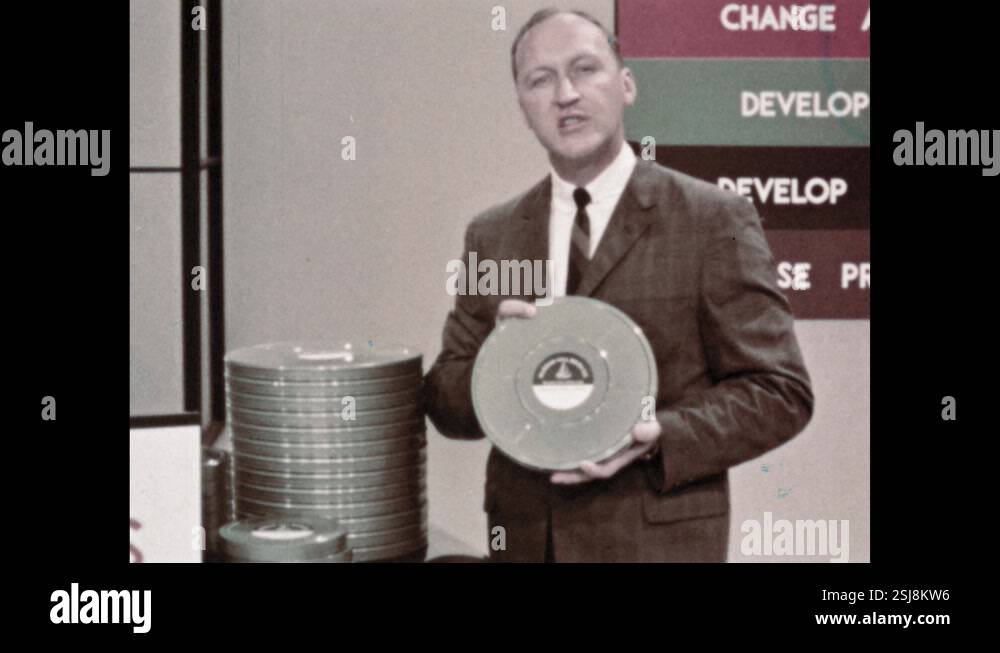 1960s: Man in suit holding film can. Labels placed on the film can ...