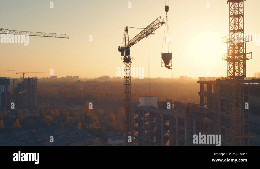 Aerial side view of a tower cranes silhouettes at the construction site ...