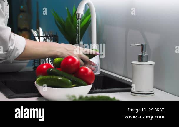 household routine, female hand washing fresh vegetables before cooking ...