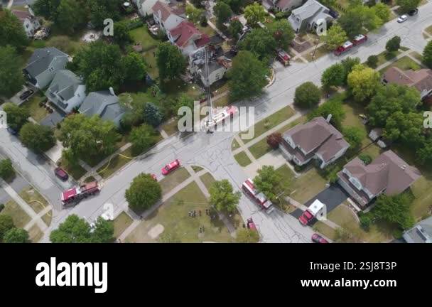 Wide Shot of a burned house in suburbs and firemen spray water on fire ...