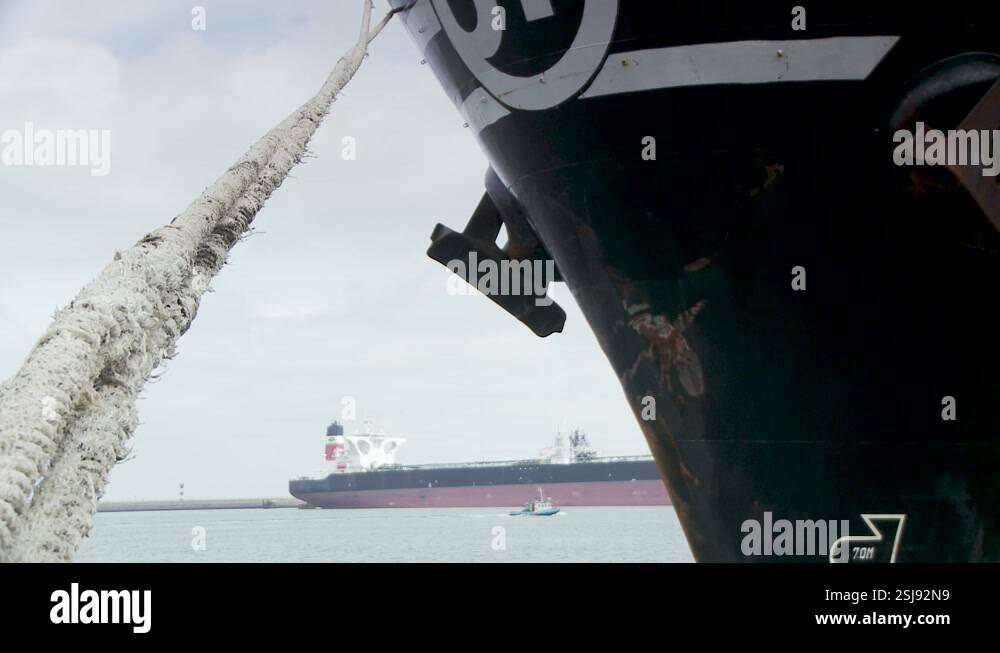 Close-up bow of a big container ship tied with thick rope, harbour and ...