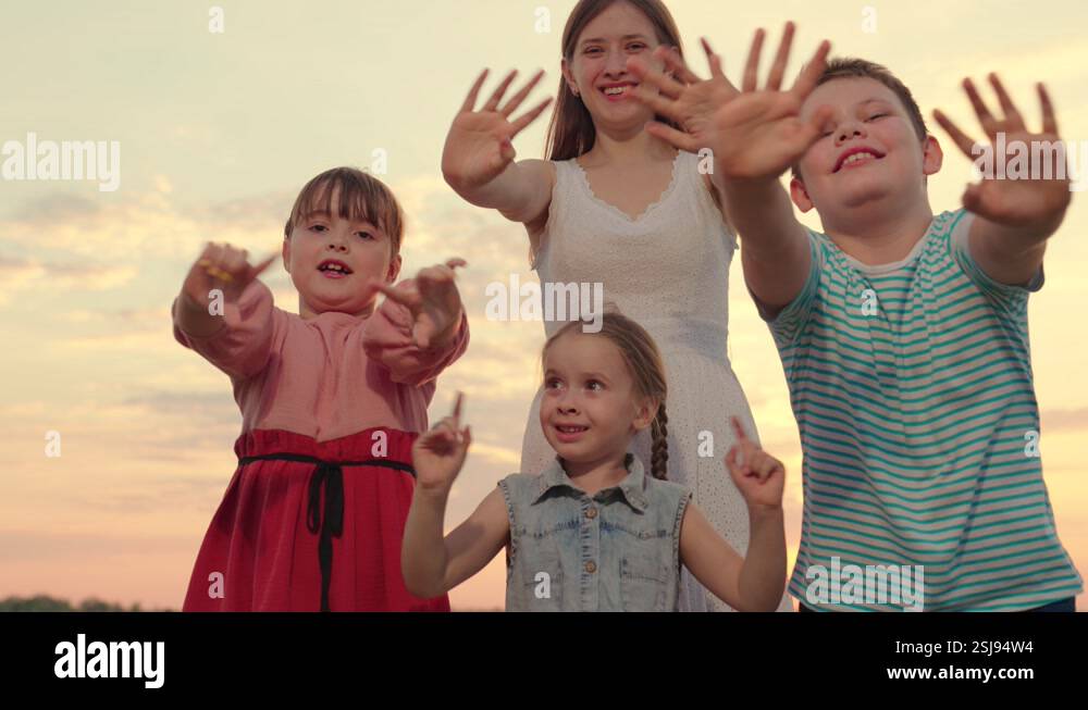 Mother, children play in park. Mom, Children happily wave their hands ...