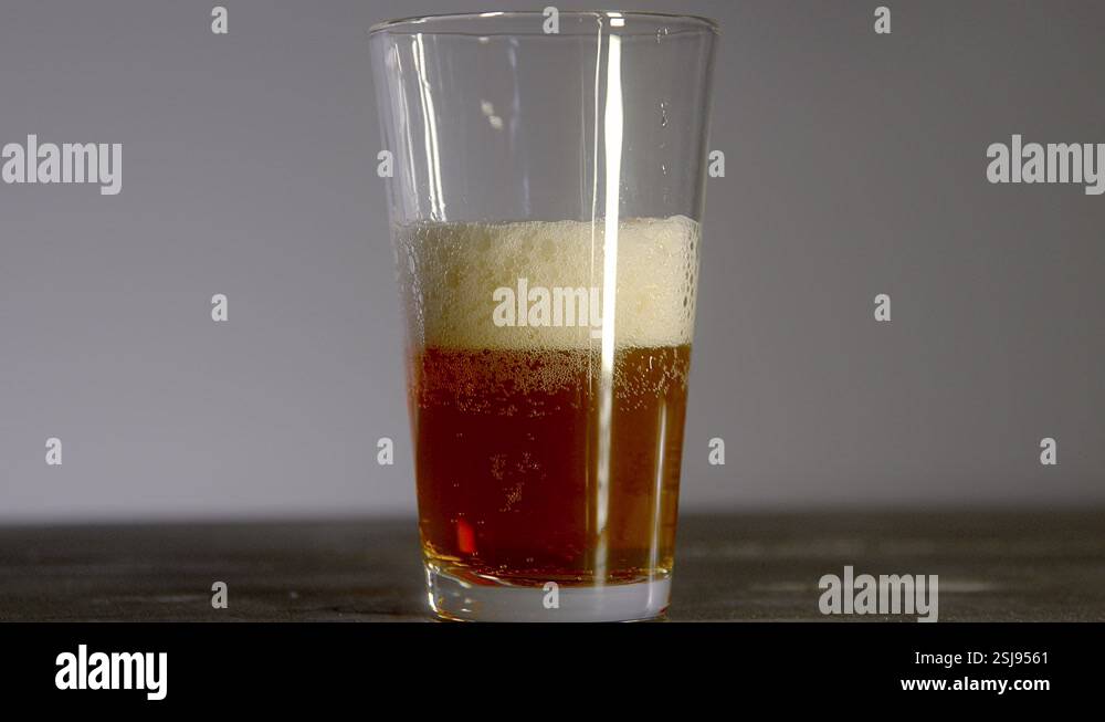 Beer being poured into pint glass to from half filled to full on black ...