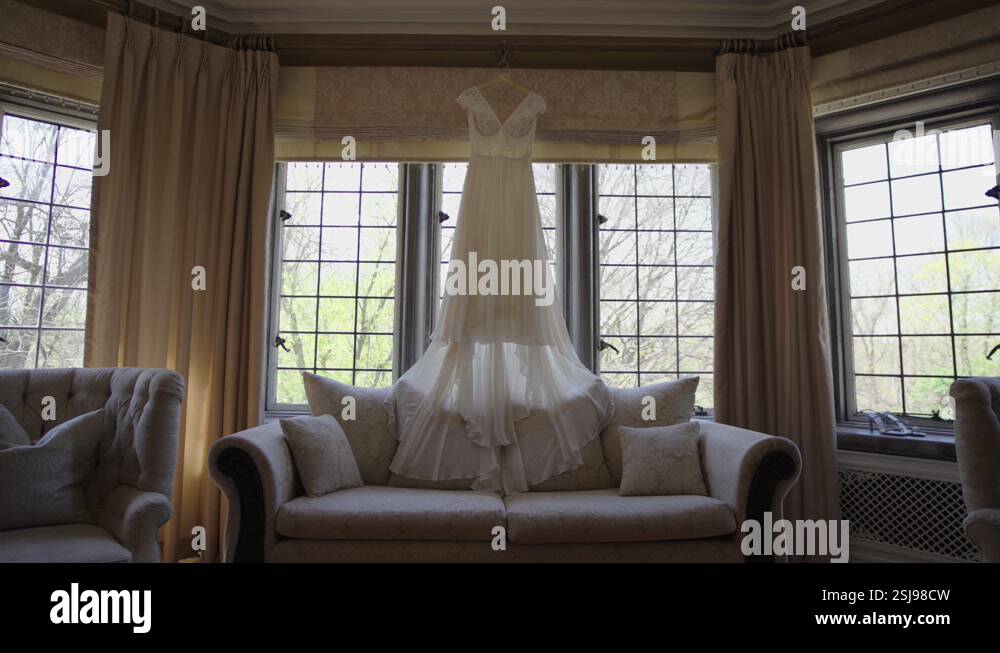 Backlit wedding dress hanging in mansion house window above ornate ...