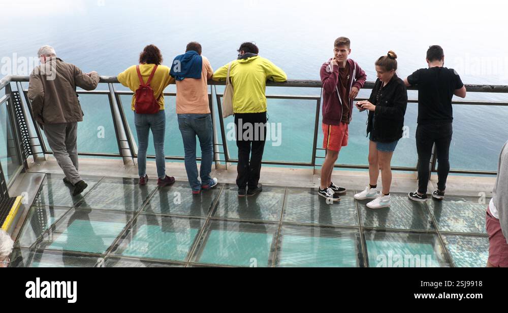 Tourists on a glass viewing platform above the steep sea cliffs on Cabo ...