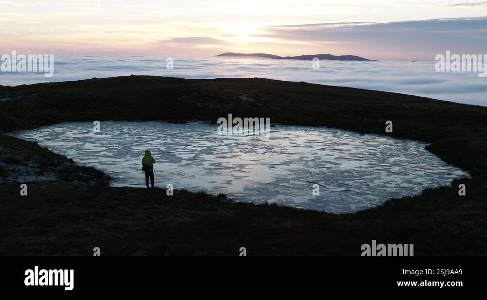 A mountaineer infront of Ice patterns on a frozen tarn on the summit of ...