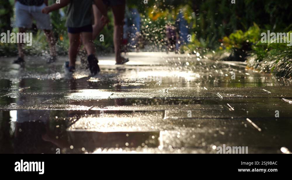 Happy boy running over puddles with mom, low camera position and soft ...