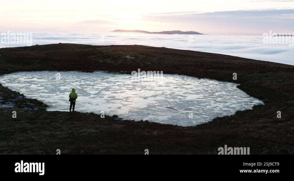 A mountaineer infront of Ice patterns on a frozen tarn on the summit of ...