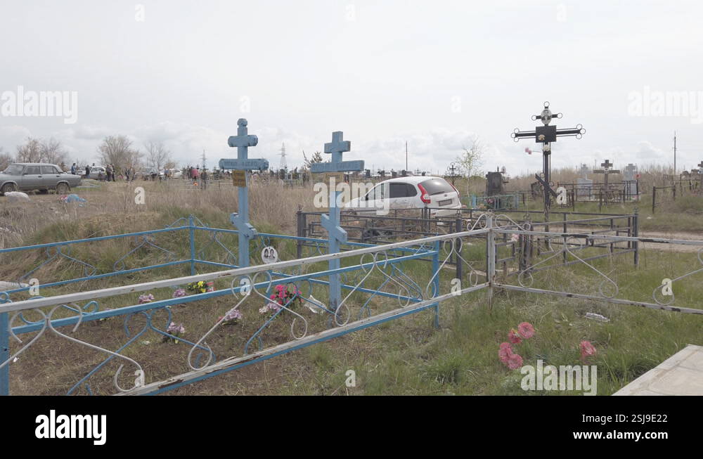 People and cars in the provincial Russian cemetery among the graves of ...