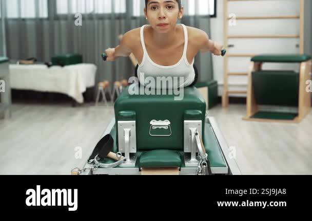 Happy woman practicing back extension on pilates chair to improve core ...