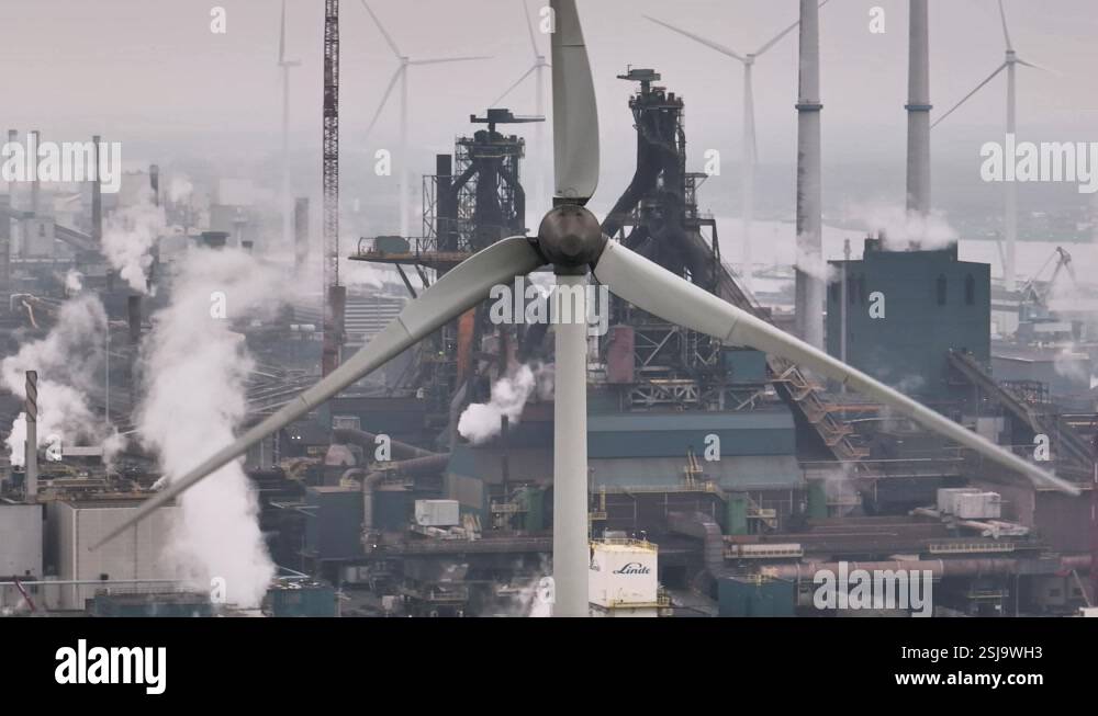 Close up orbiting view of a wind turbine in a dense industrial complex ...