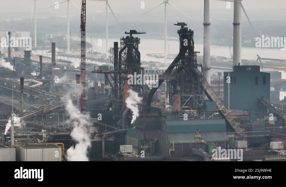 Aerial medium shot of Tata steel mill with wind turbines in the Stock ...