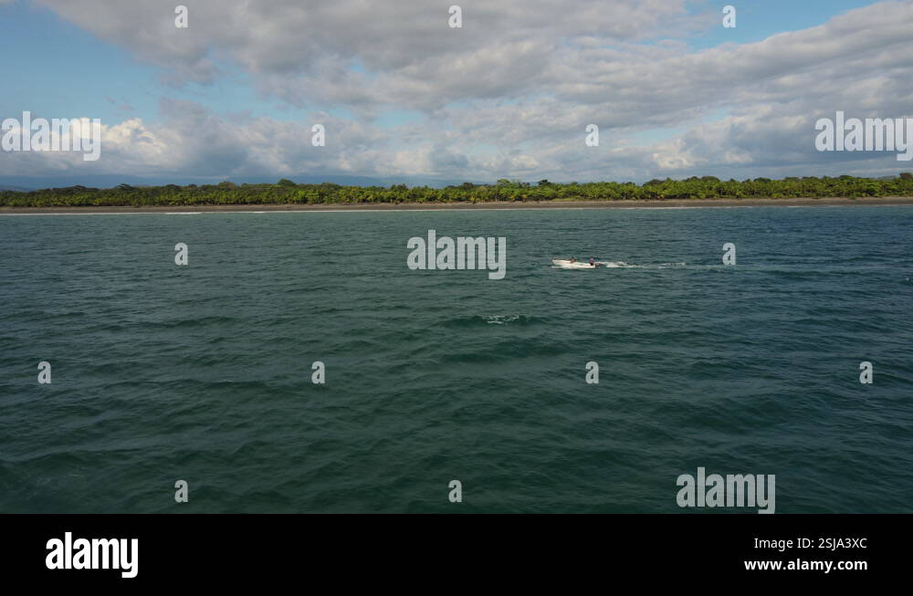Aerial tracking shot of a fishing boat along the Costa Rican coast ...