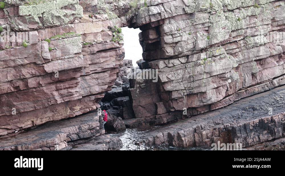 A man climbing on a sea arch at Culkein near Stoer, Assynt, Scotland ...