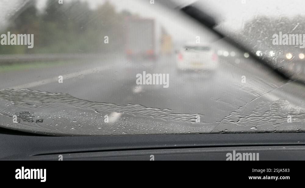 Rain water on a wind shield of a car driving in the rain on the M74 ...