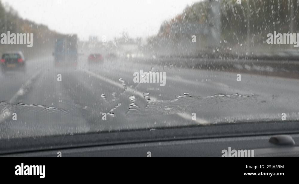 Rain water on a wind shield of a car driving in the rain on the M74 ...