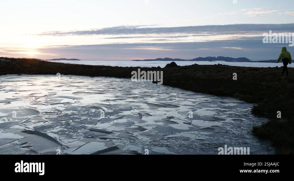 A mountaineer infront of Ice patterns on a frozen tarn on the summit of ...