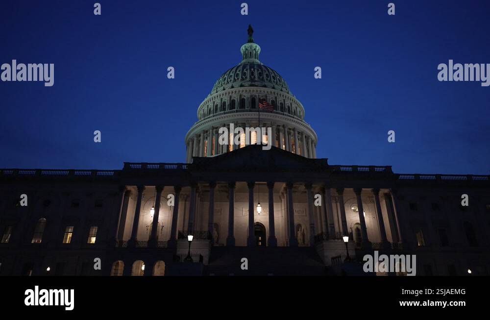 Slow motion to right showing the US Capitol with lights and flags ...