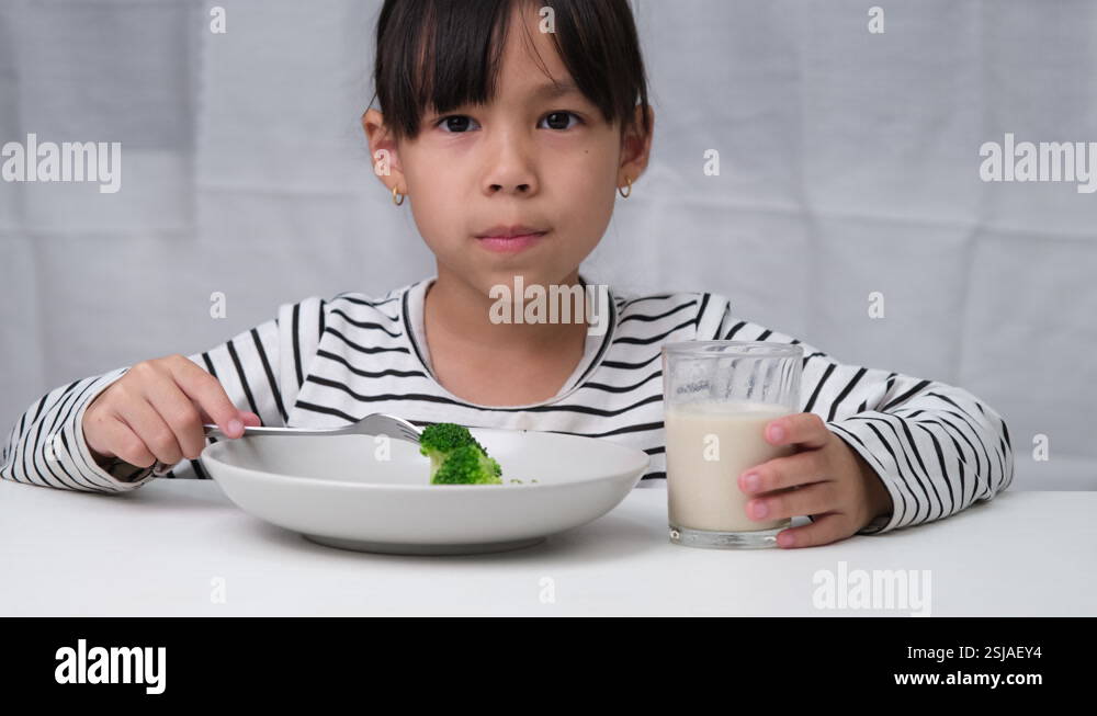 Little girl eats healthy vegetables and milk for her meals. Healthy ...