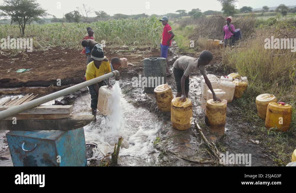 Kids fill plastic containers with drinkable water by borehole wall in ...