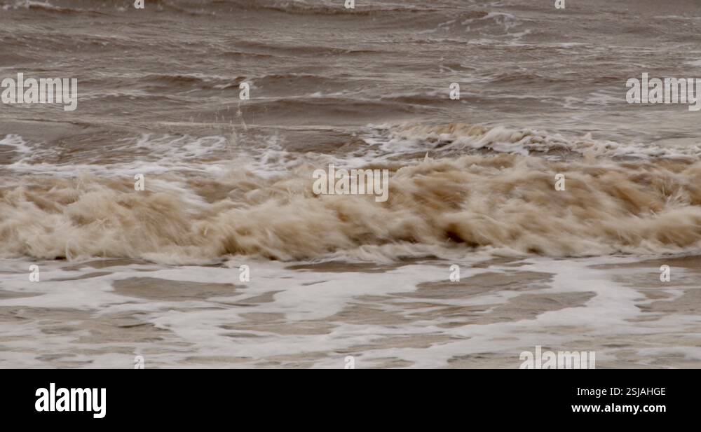 Mid shot of cold bleak looking winter waves breaking on to Ingoldmells ...