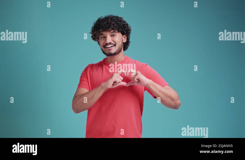 Handsome latin spanish guy showing heart-shaped gesture over his chest ...
