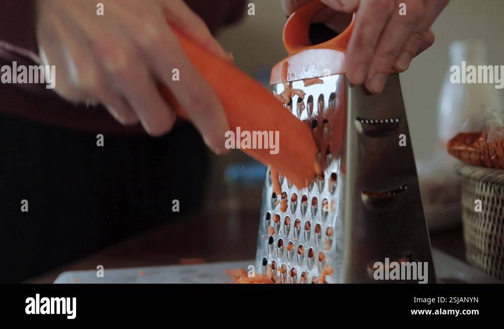 a man rubs carrots on a metal grater. a man rubs a carrot on a grater ...