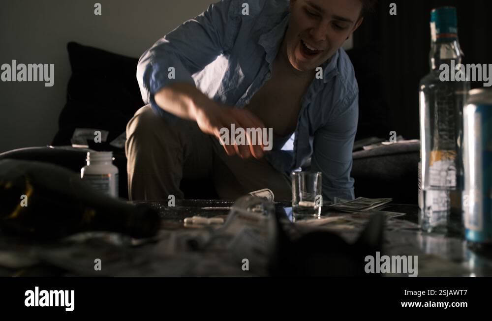 Young addicted junkie man sniffing snorting cocaine lines on mirror ...