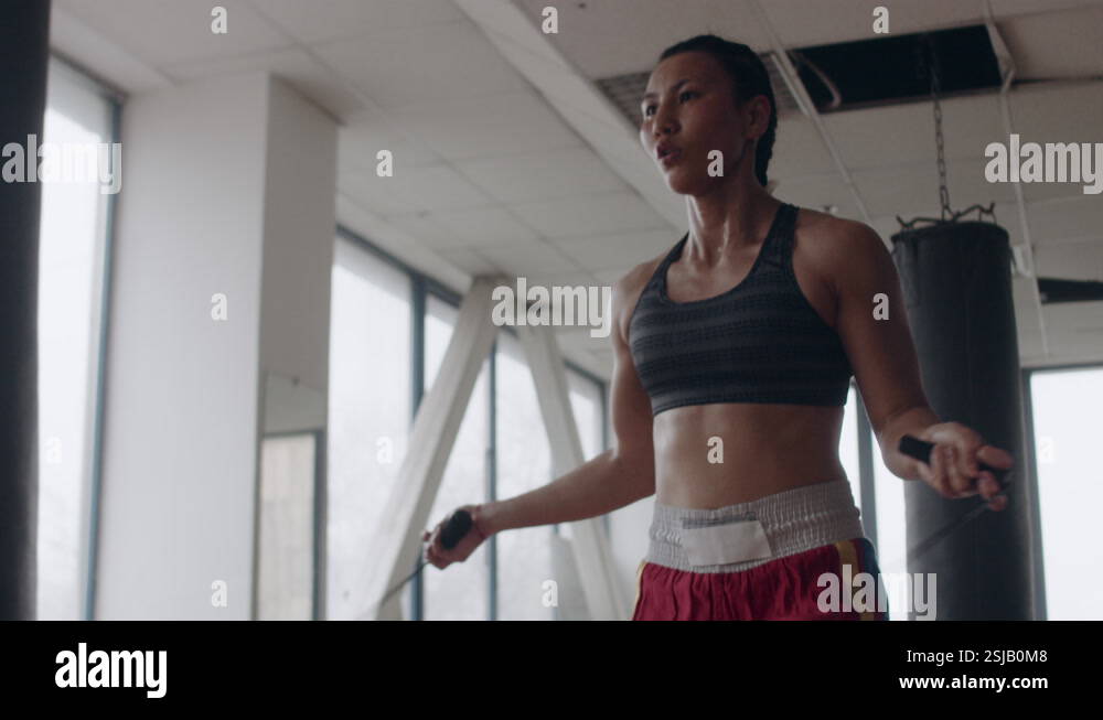 Young asian female boxer in sportswear with a confident face jumping a ...