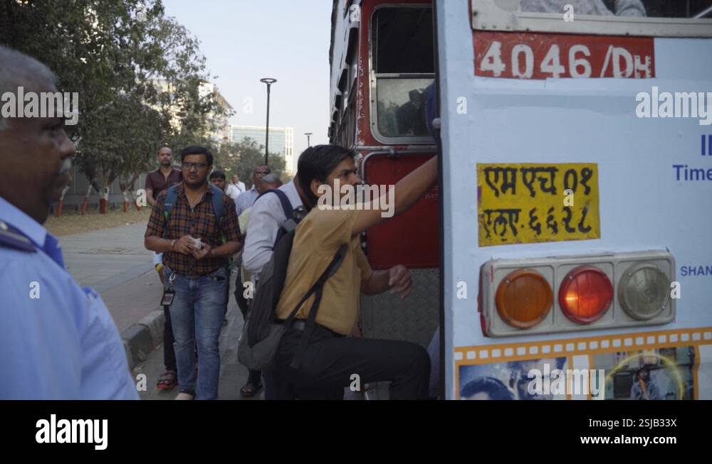 Indian people getting on a city bus in turn guided by ticket supervisor ...