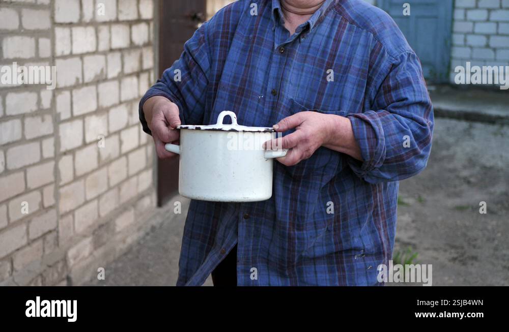 the old woman carries a pot of food in her hands. poverty, hunger ...