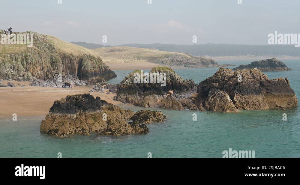 People on the beach on Llanddwyn Island, off the SW coast of Anglesey ...