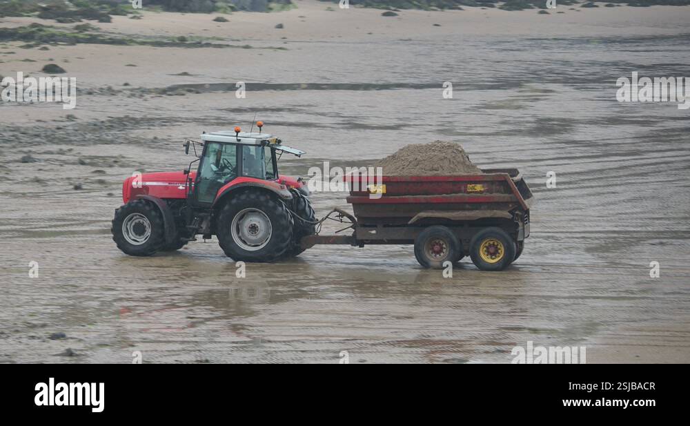 A tractor and trailer filled with sand on the beach in Abersoch, North ...