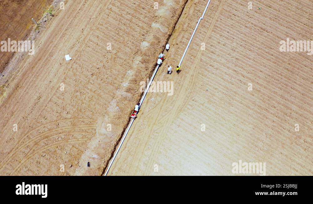 aerial rotted shot of Indian farmer and labor fittings a water pipeline ...