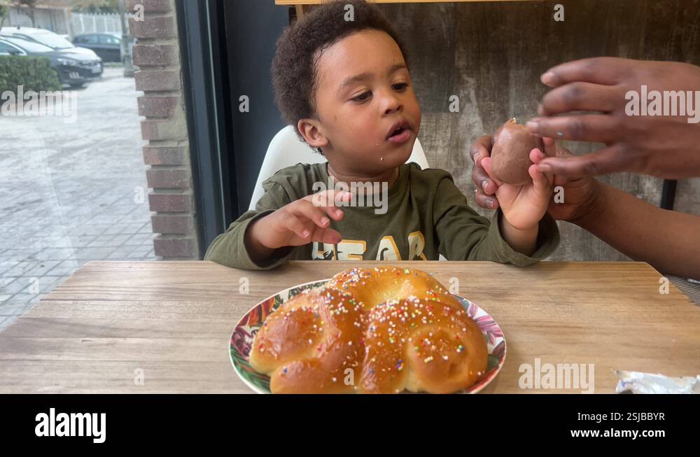 Sweet 3-year-old black child eating a chocolate Kinder Surprise and a ...