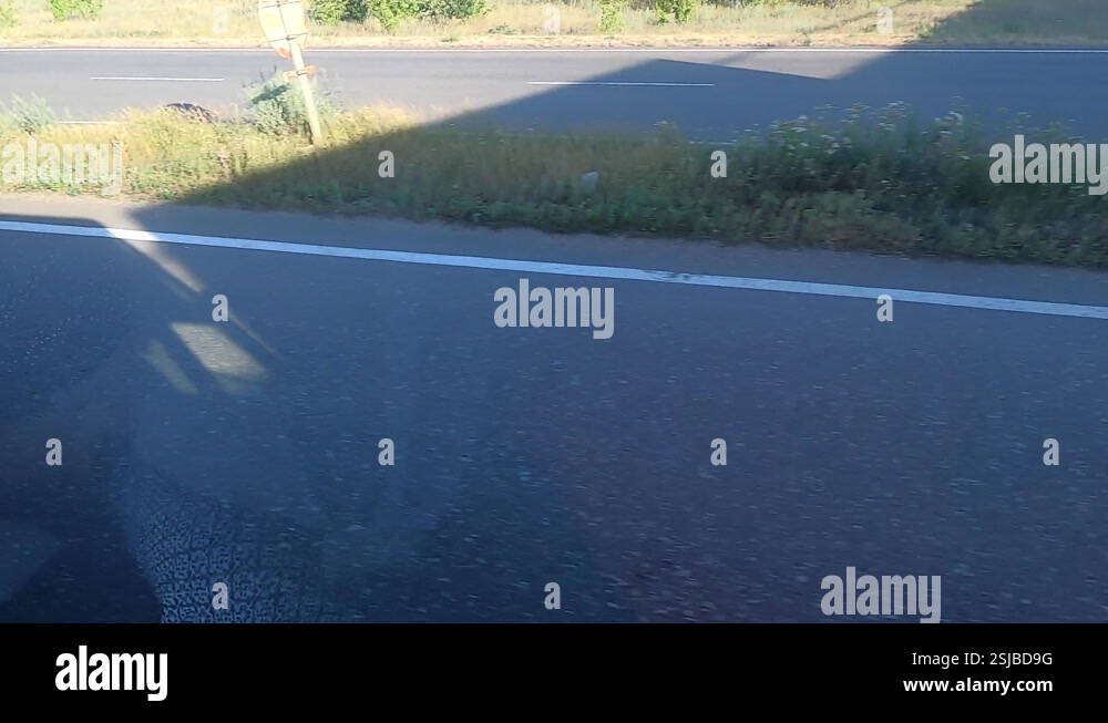 Shadow of driver's cabin of bus driving on asphalt road. View from bus ...