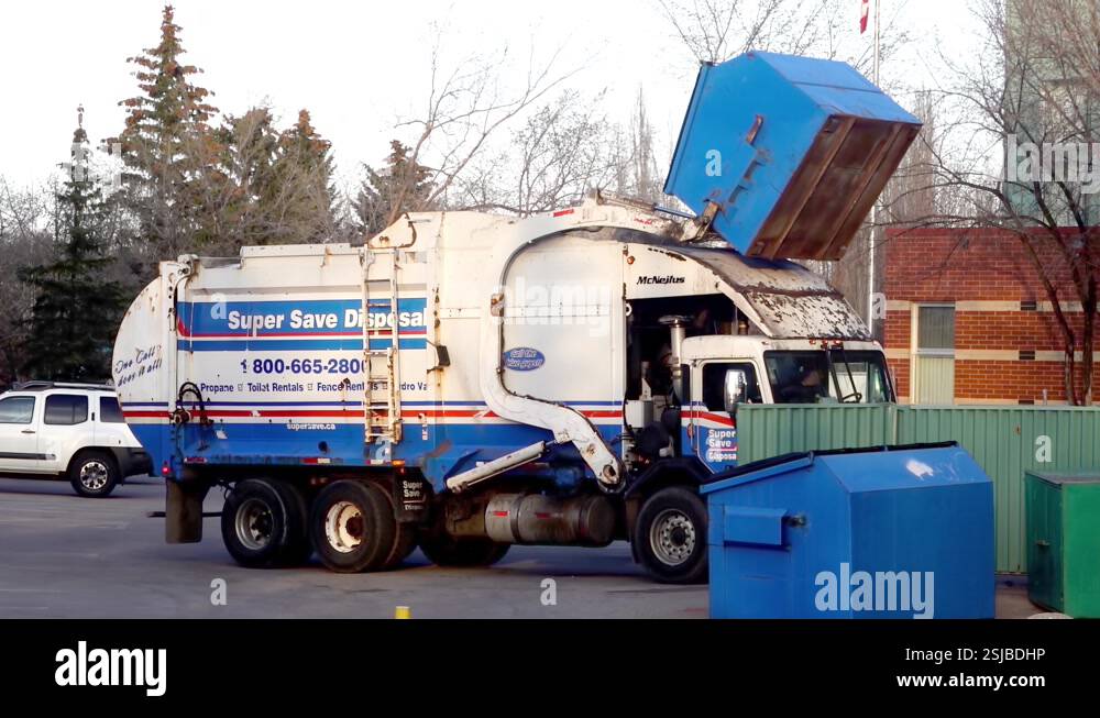A garbage truck for waste and recycling, loading a big metal blue ...